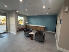 Um hall com duas poltronas, uma mesa pequena, um balcão e vista para o exterior.