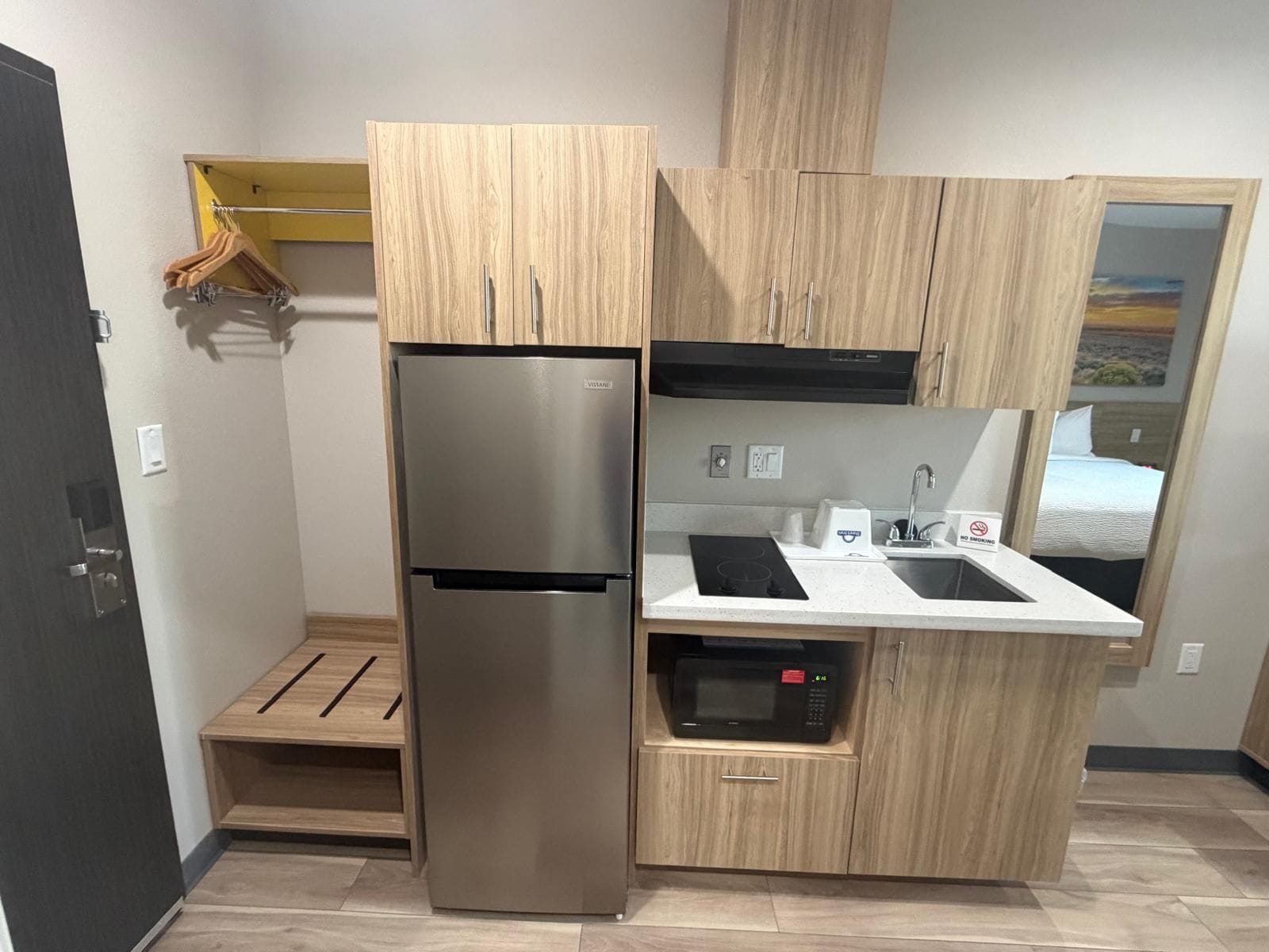 Cozinha compacta com geladeira de aço inoxidável, micro-ondas e pia.