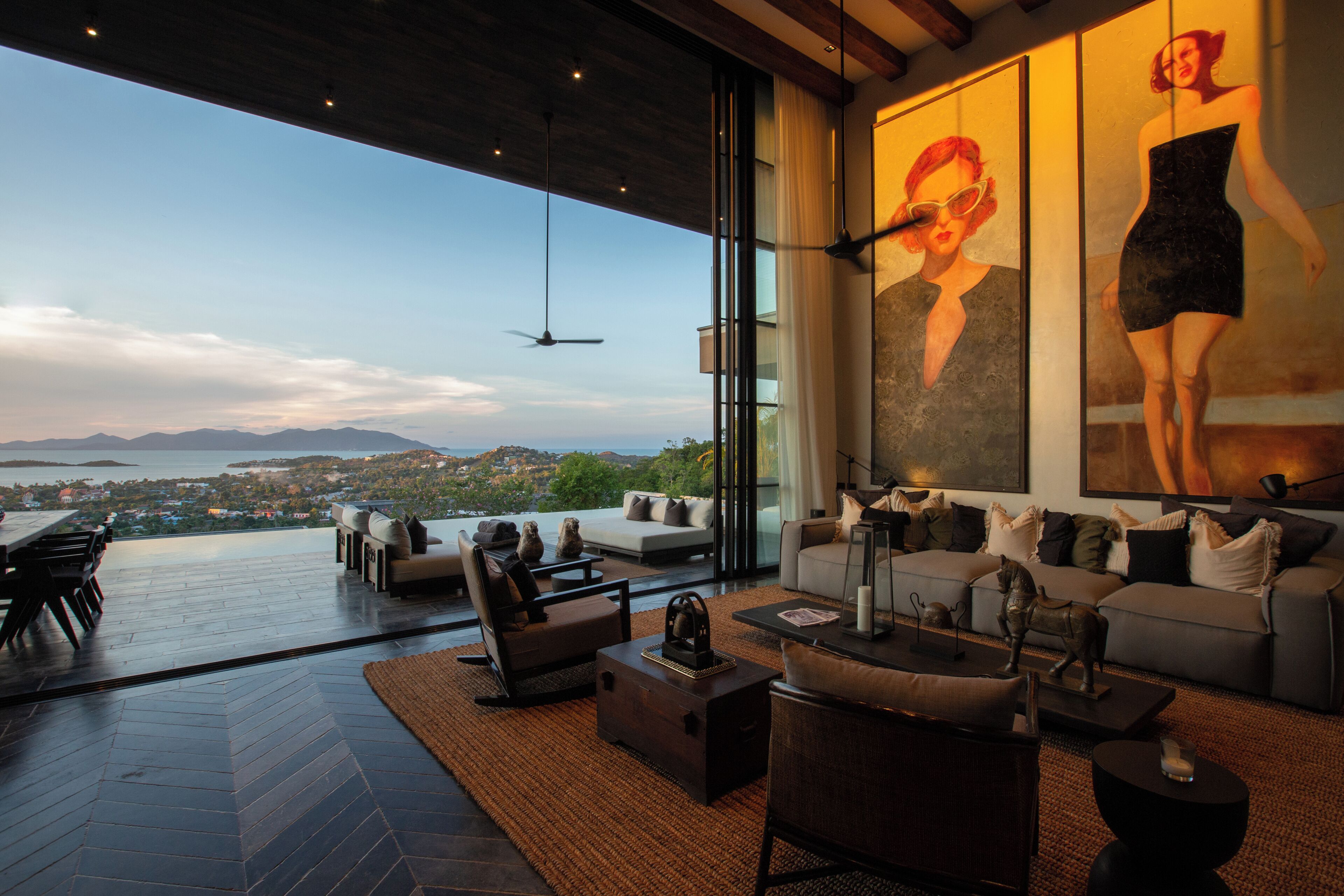 Uma sala de estar moderna com uma grande janela que oferece uma vista panorâmica, mobiliada com sofás, uma mesa de centro e objetos decorativos.