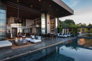 Área moderna da piscina com espaço para refeições e assentos.