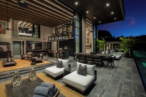 Ampla área externa com diversas opções de assento, piscina e design arquitetônico moderno.