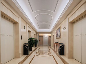 Corredor de hotel com piso polido, um desenho circular no centro e portas em ambos os lados.