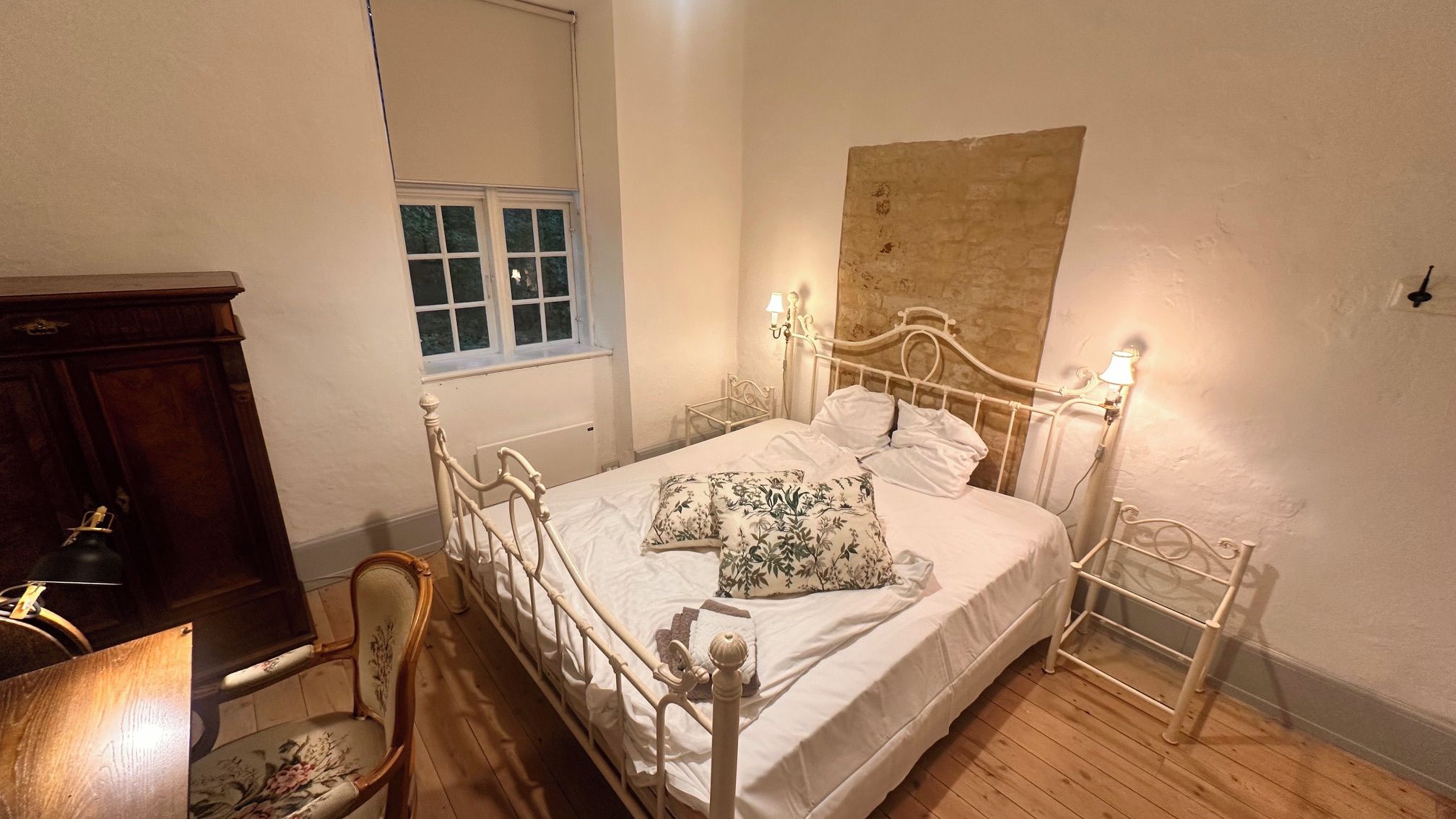 Quarto com uma cama de solteiro, uma cadeira de madeira, cômoda e janela.