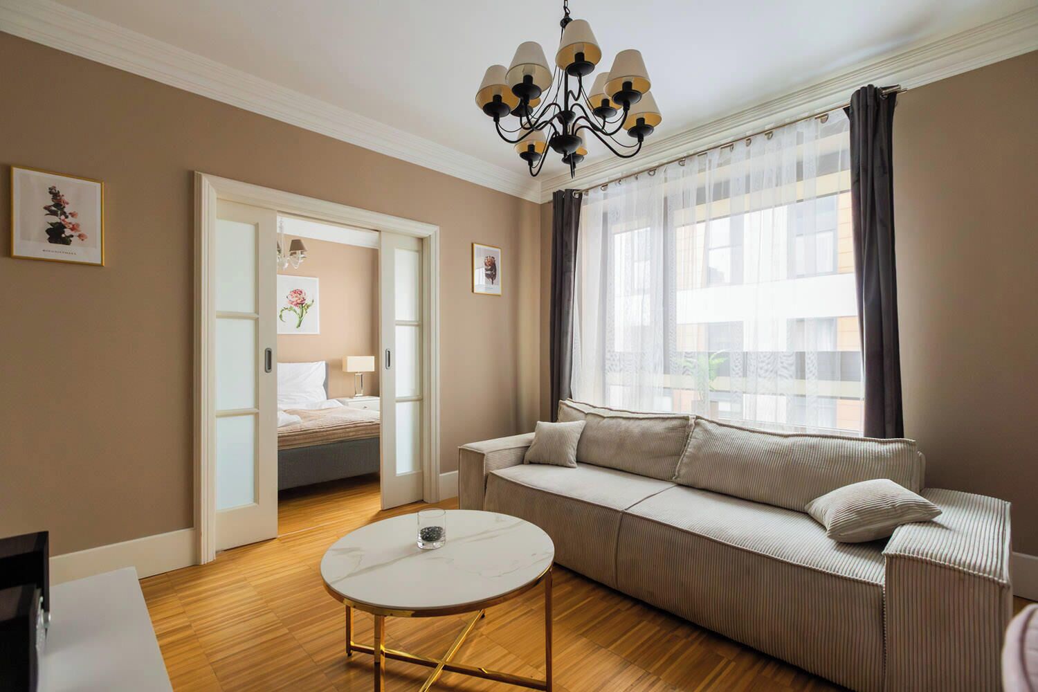 Uma sala de estar moderna com um sofá, uma mesa de centro de vidro e um lustre.