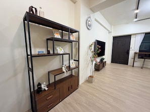 Uma sala de estar moderna com um armário de madeira, uma TV fixada na parede e uma planta decorativa.