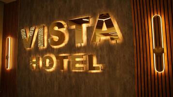 Pareda com letras iluminadas formando a palavra 'VISTA HOTEL'.