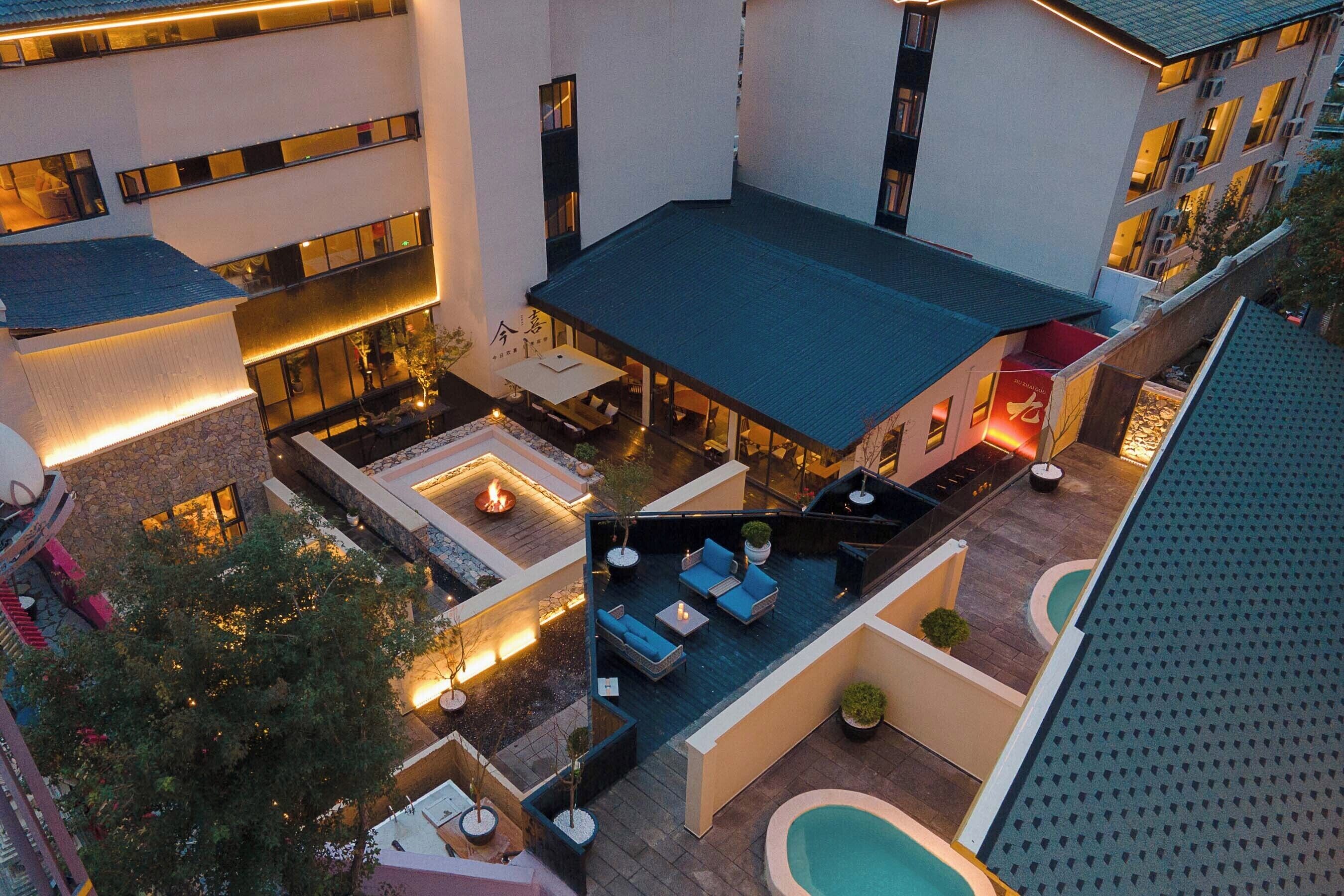 Vista aérea de um pátio de hotel com áreas de estar ao ar livre, piscina e lareira.
