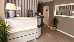 Uma área de recepção com balcão, luminária, sinalização para Google Pay e uma porta com a inscrição 'LWC'.