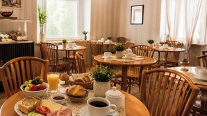 Mesa posta para dois com pão torrado, frutas, ovos e uma xícara de café.