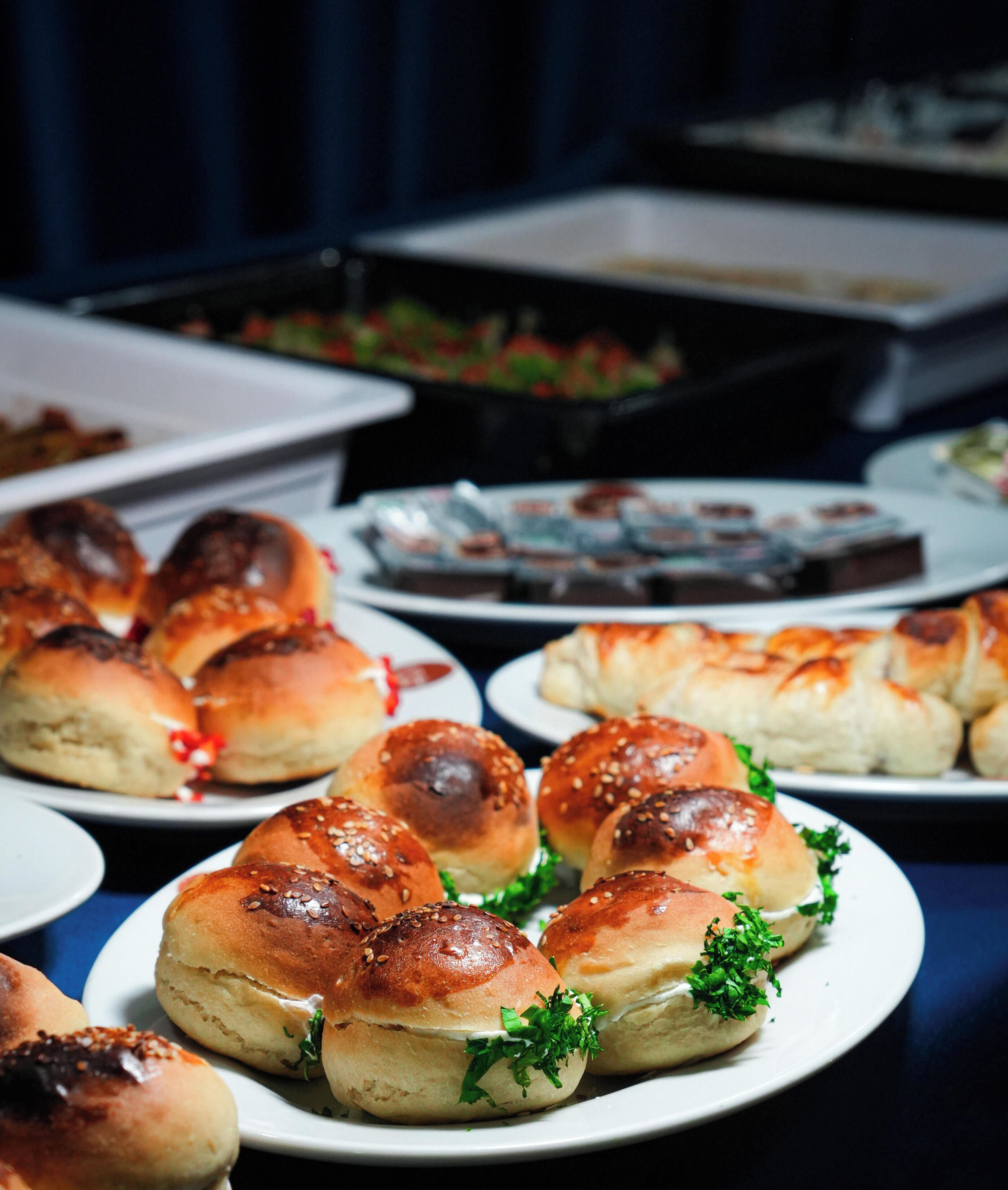 Mesa de buffet com diversos alimentos, incluindo pães decorados com ervas.