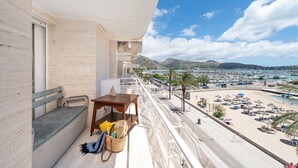 Uma varanda com vista para a praia, uma mesa, um banco e uma cesta de vime.