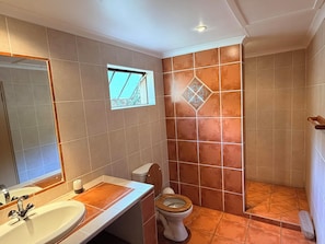 Casa de banho com lavatório, espelho, sanita e zona de duche.