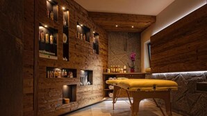 Um quarto de spa com paredes de madeira, prateleiras com garrafas, uma mesa de massagem e uma parede de pedra.