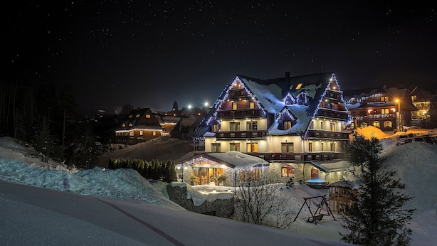 Paisagem coberta de neve com um edifício de vários andares decorado com luzes de Natal.