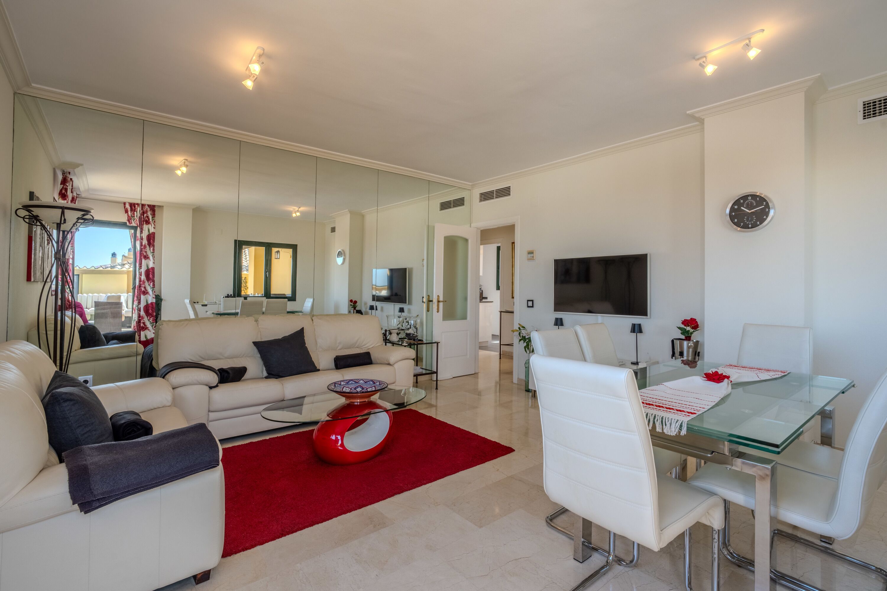 Uma sala de estar moderna com sofá, mesa de centro e espaço para refeições.