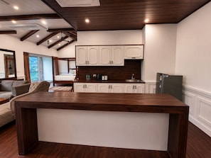 Cozinha moderna com armários brancos, uma ilha de madeira e um espaço de refeições com sofá.
