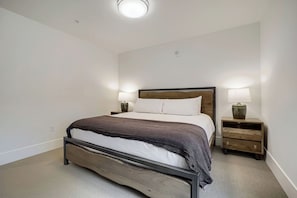 Um quarto com uma cama, duas mesinhas de cabeceira e um criado-mudo.