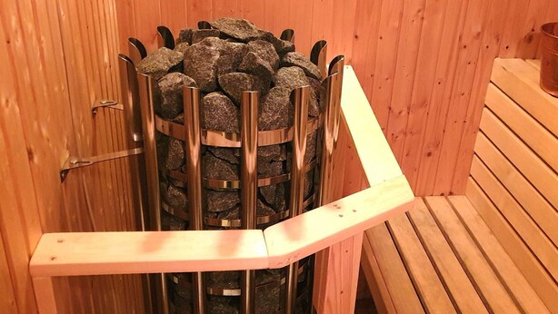 Uma sauna com parede de pedra e grelha de metal.