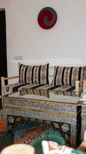 Uma cama com colcha estampada, um painel decorativo na parede e cabeceira de madeira.