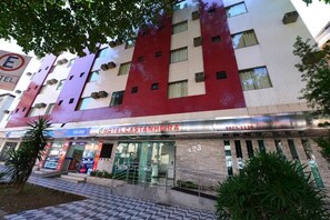 Um hotel com fachada em vermelho e branco, entrada visível e o número 823 na fachada.