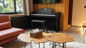 Uma sala de estar moderna com um piano, uma televisão e um sofá.