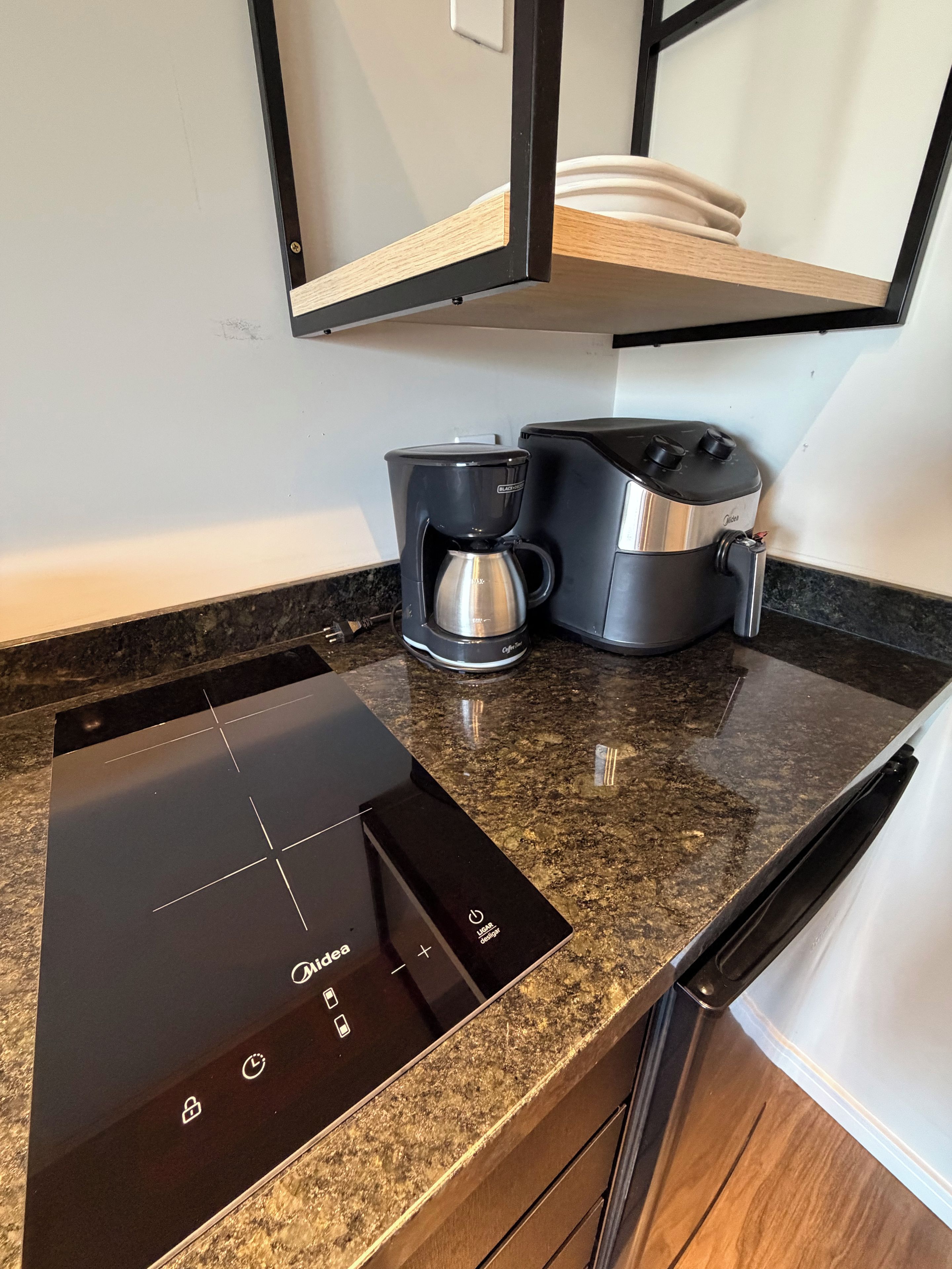 Cozinha equipada com fogão por indução embutido, cafeteira e torradeira.