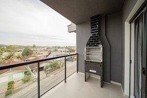 Varanda com grade preta e vista para uma área residencial.