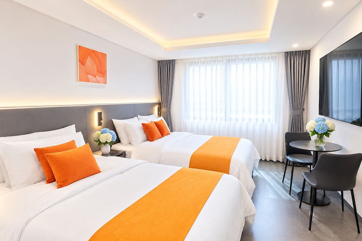 Quarto de hotel com duas camas, uma mesa e uma cadeira.