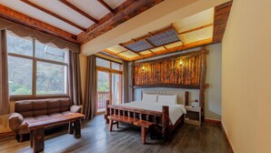 Quarto com uma cama, um banco e uma janela com cortinas.