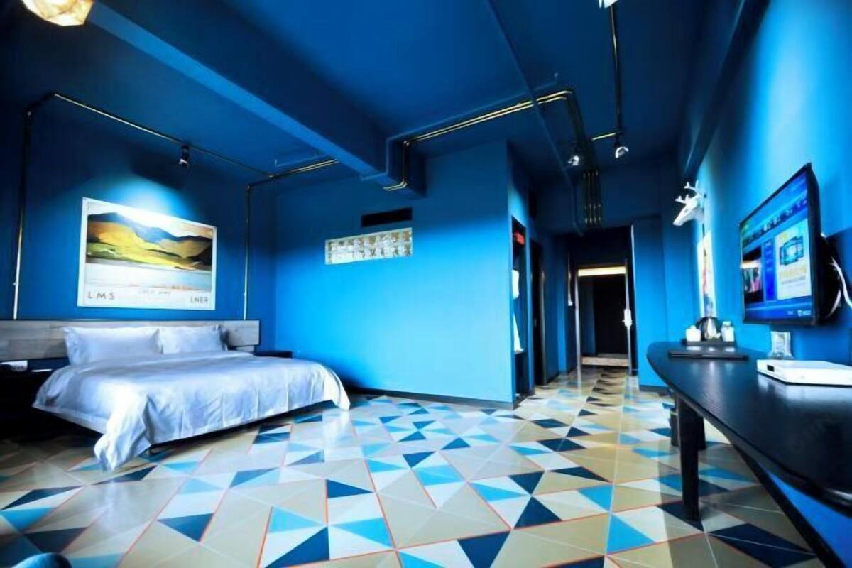 Quarto de hotel com uma cama, uma escrivaninha e um computador.
