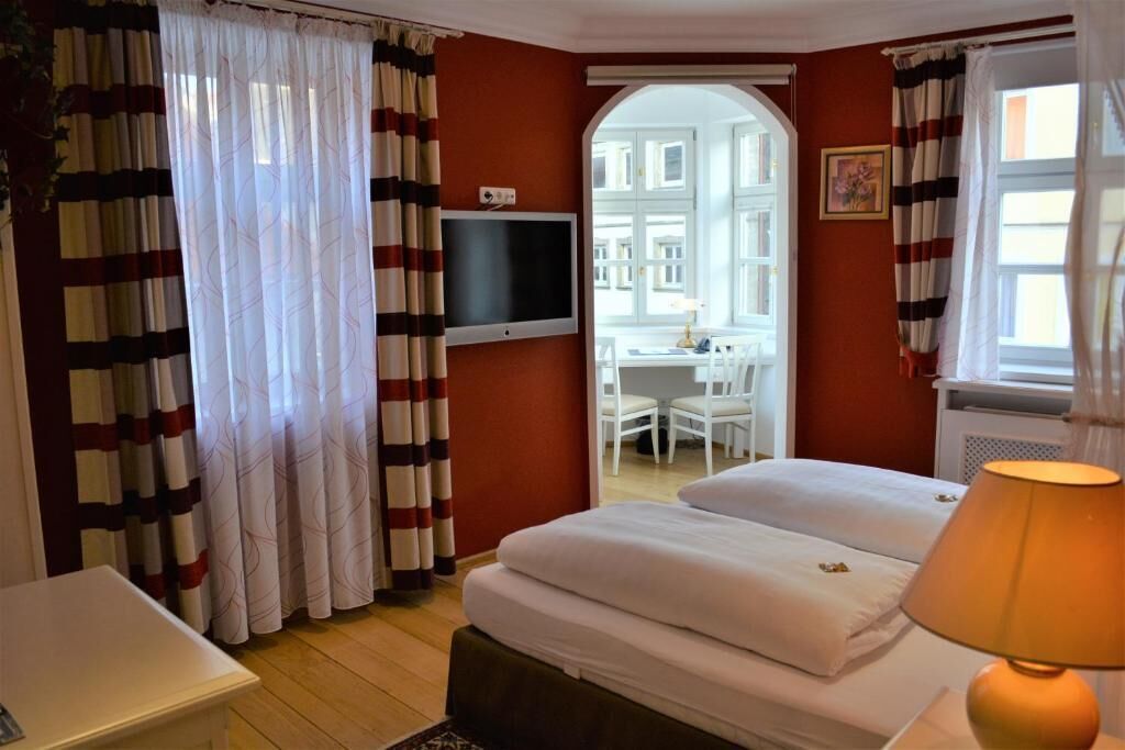 Quarto de hotel com cama, televisão, escrivaninha e cadeira.