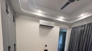 Quarto com cama, escrivaninha, ar-condicionado e ventilador de teto.