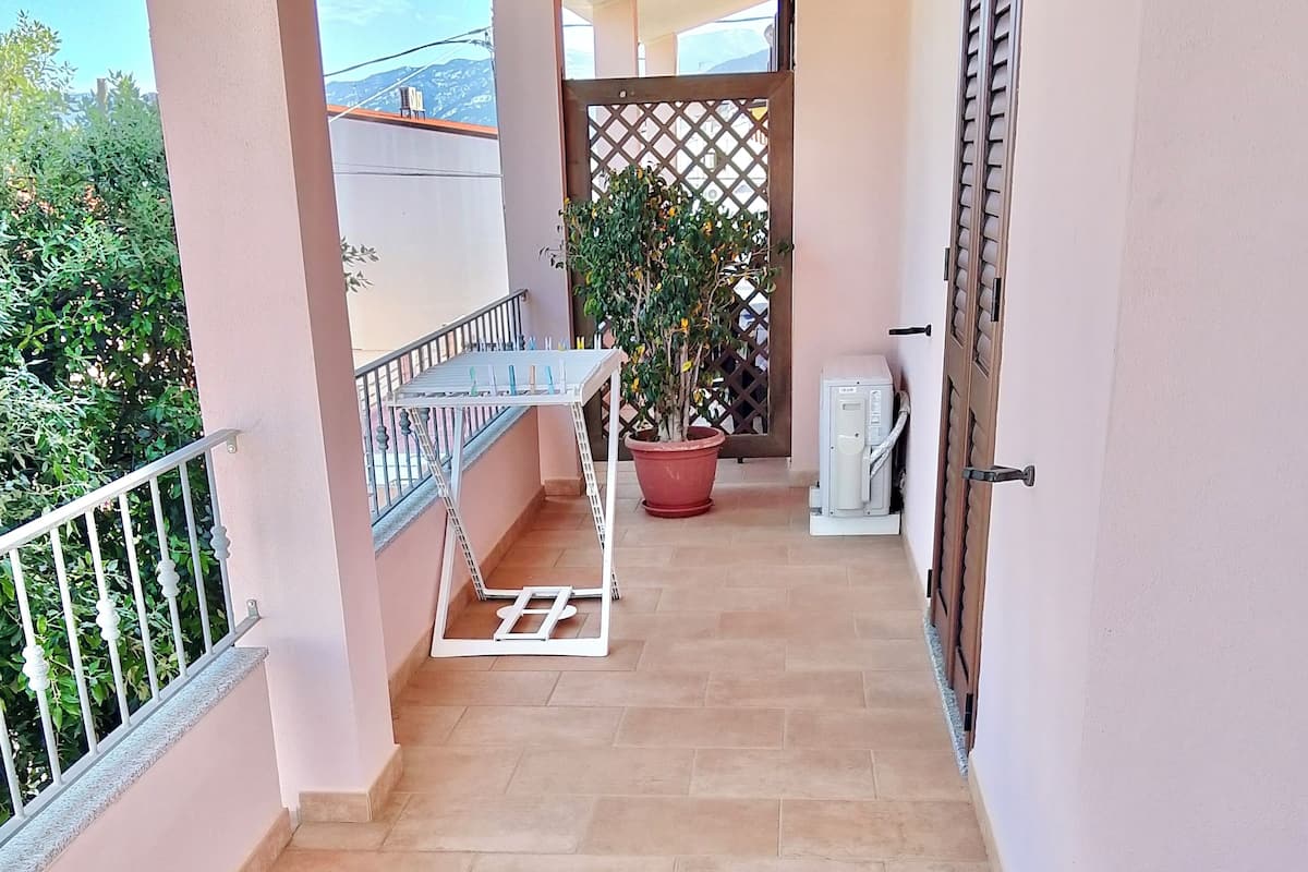 Uma varanda com guarda-corrimão de metal, um vaso de planta e um eletrodoméstico branco.