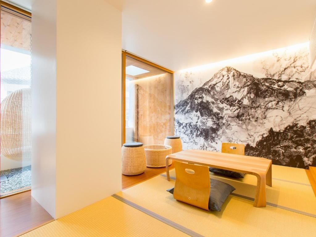 Quarto moderno com mesa de madeira, cadeiras e um grande mural na parede com montanhas.