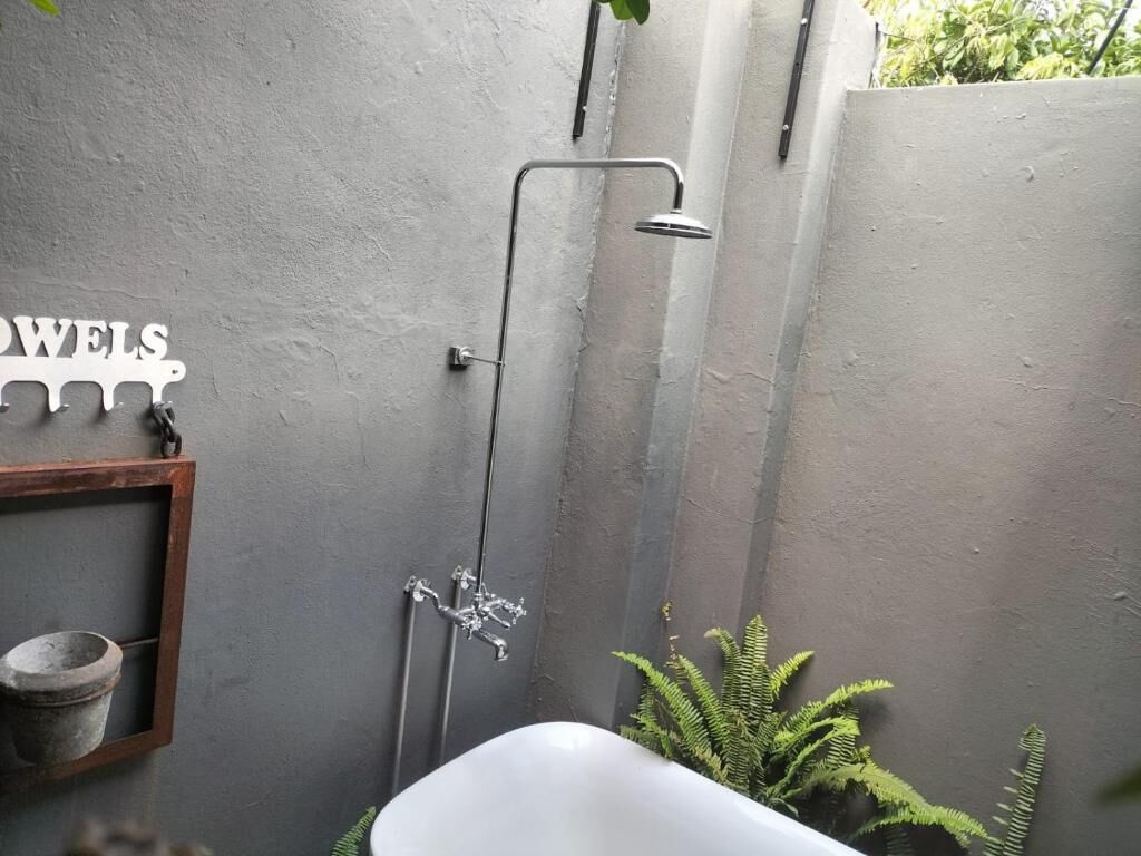 Casa de banho com chuveiro, um porta-toalhas e uma pequena prateleira com um balde.