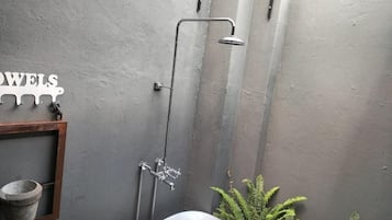 Casa de banho com chuveiro, um porta-toalhas e uma pequena prateleira com um balde.
