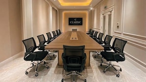 Uma sala de conferências com uma mesa comprida, cadeiras pretas e um letreiro com a inscrição 'CLASSYC' na parede.