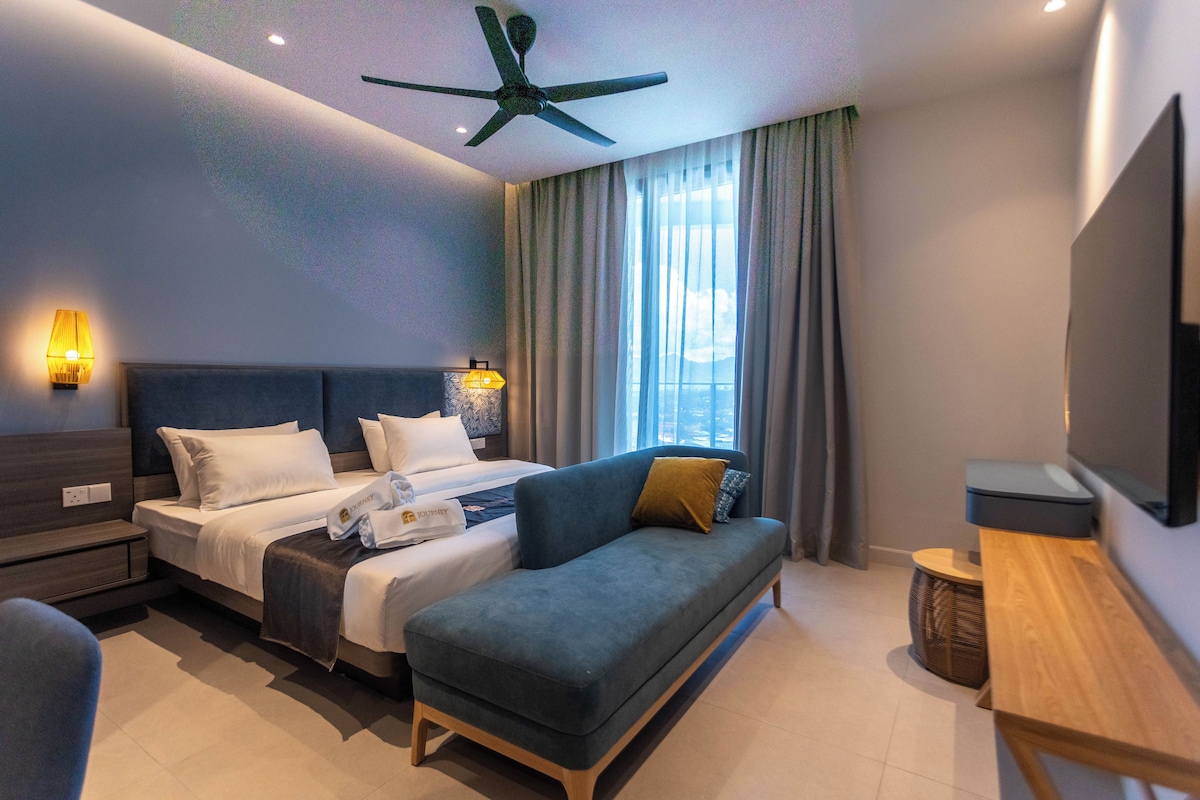 Quarto de hotel moderno com cama, sofá, ventilador de teto e TV.