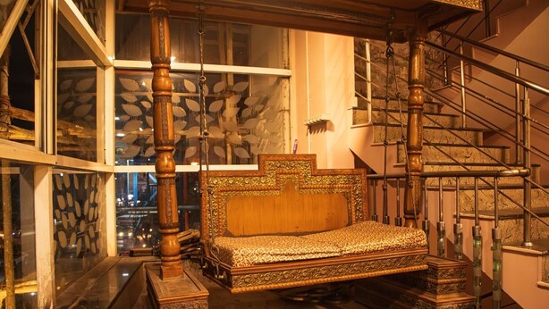 Uma cama com cabeceira e peseira elaboradas, uma escada de madeira e uma janela com vista decorada.