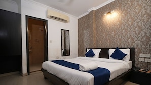 Quarto de hotel com cama, porta, ar condicionado e parede com desenho estampado.