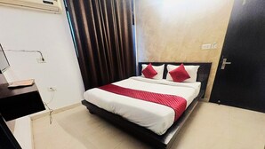 Quarto de hotel com cama, escrivaninha, cadeira e porta.