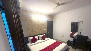 Quarto de hotel com uma cama, uma escrivaninha, um espelho e uma porta.
