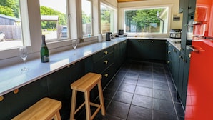 Cozinha com área de bar, janelas amplas e eletrodoméstico vermelho.