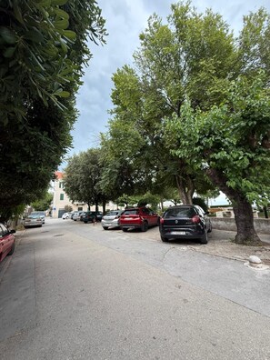 Uma rua com carros estacionados e árvores.