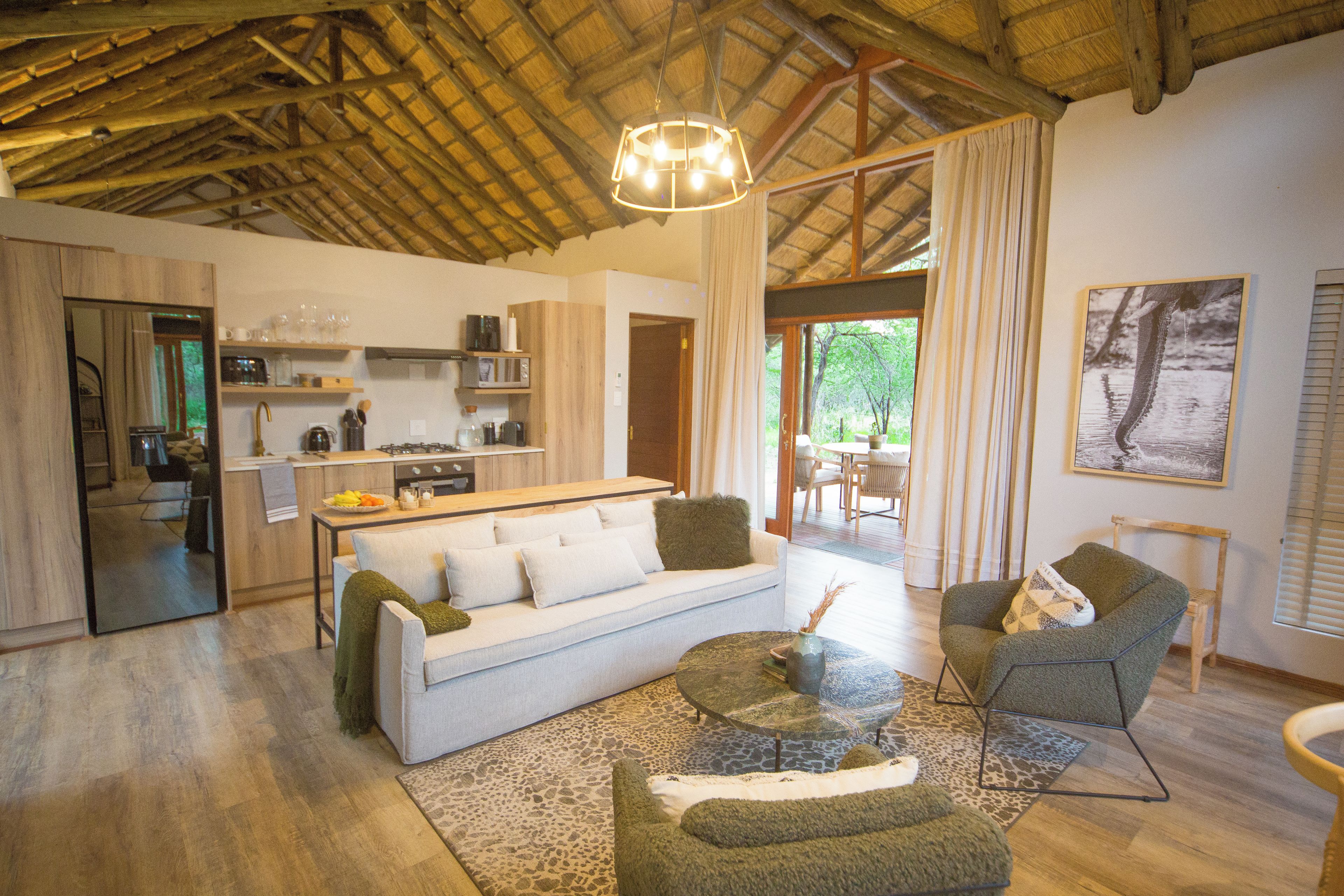 Um interior moderno com sofá, poltronas, mesa de centro e cozinha.