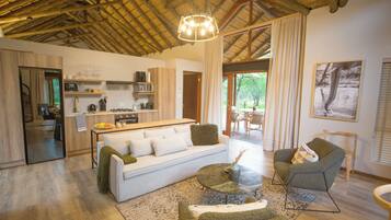 Um interior moderno com sofá, poltronas, mesa de centro e cozinha.