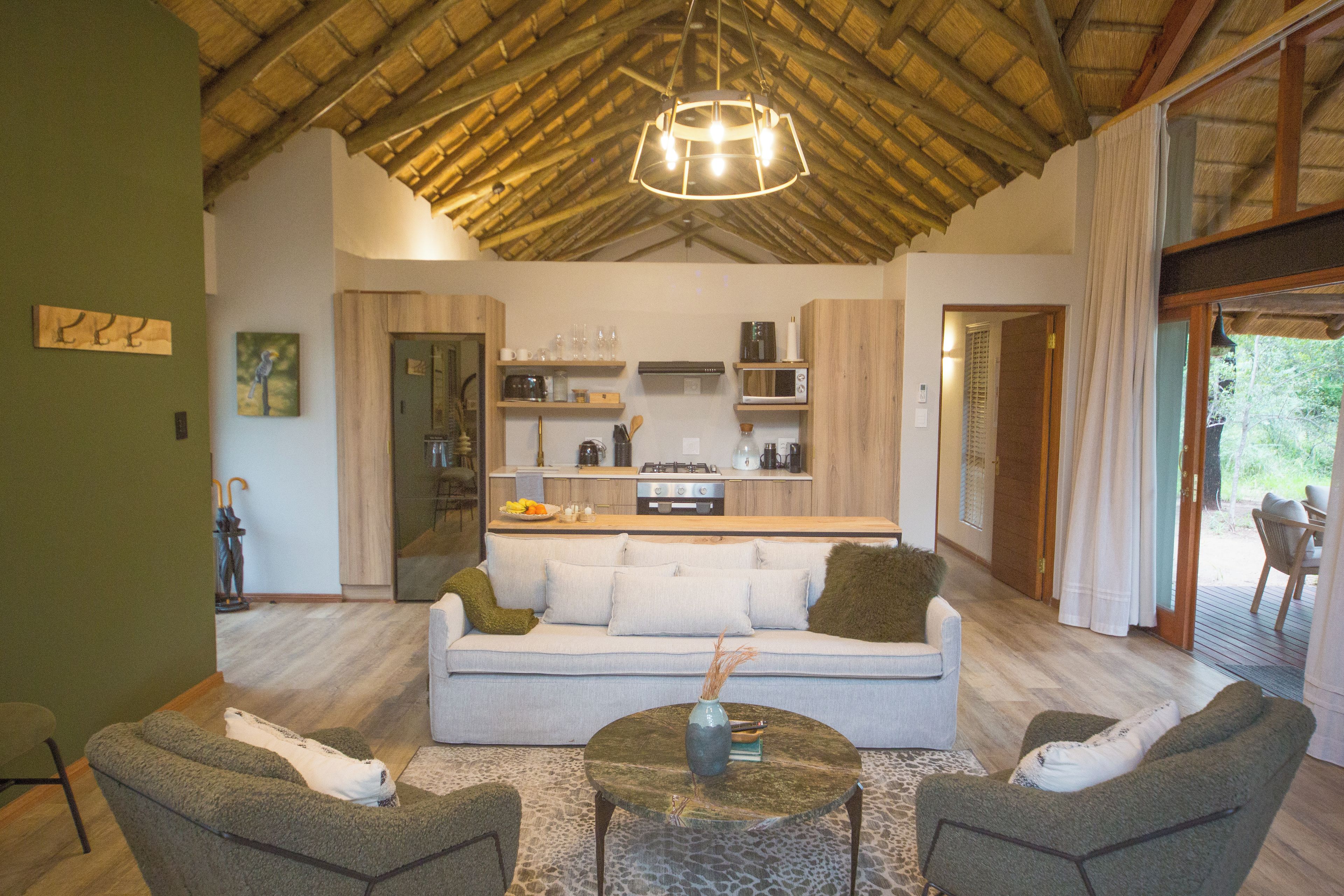 Cozinha moderna com ilha central, armários de madeira e área de jantar com sofá e cadeiras.