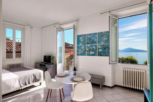 Quarto moderno com cama, escrivaninha, cadeira e mesa com uma garrafa de vinho e copos.