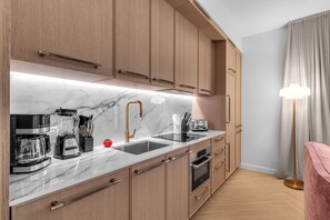 Cozinha moderna com bancadas de mármore, eletrodomésticos de aço inoxidável e armários de madeira.