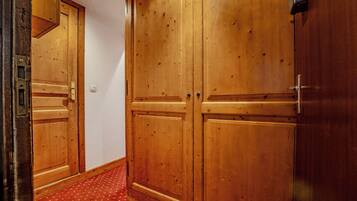 Um corredor com portas duplas de madeira, um tapete vermelho estampado e um luminário no teto.